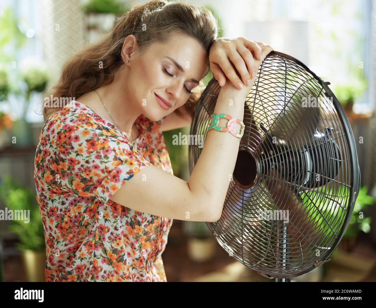 Summer heat. relaxed modern female in floral blouse in the modern house ...