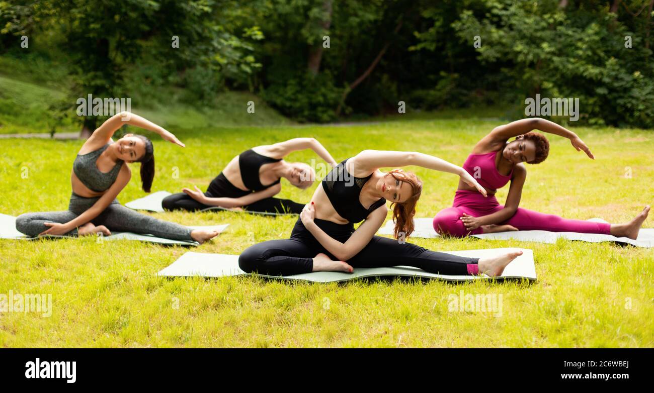 Wellbeing concept. Pretty young women doing yoga exercises at park ...