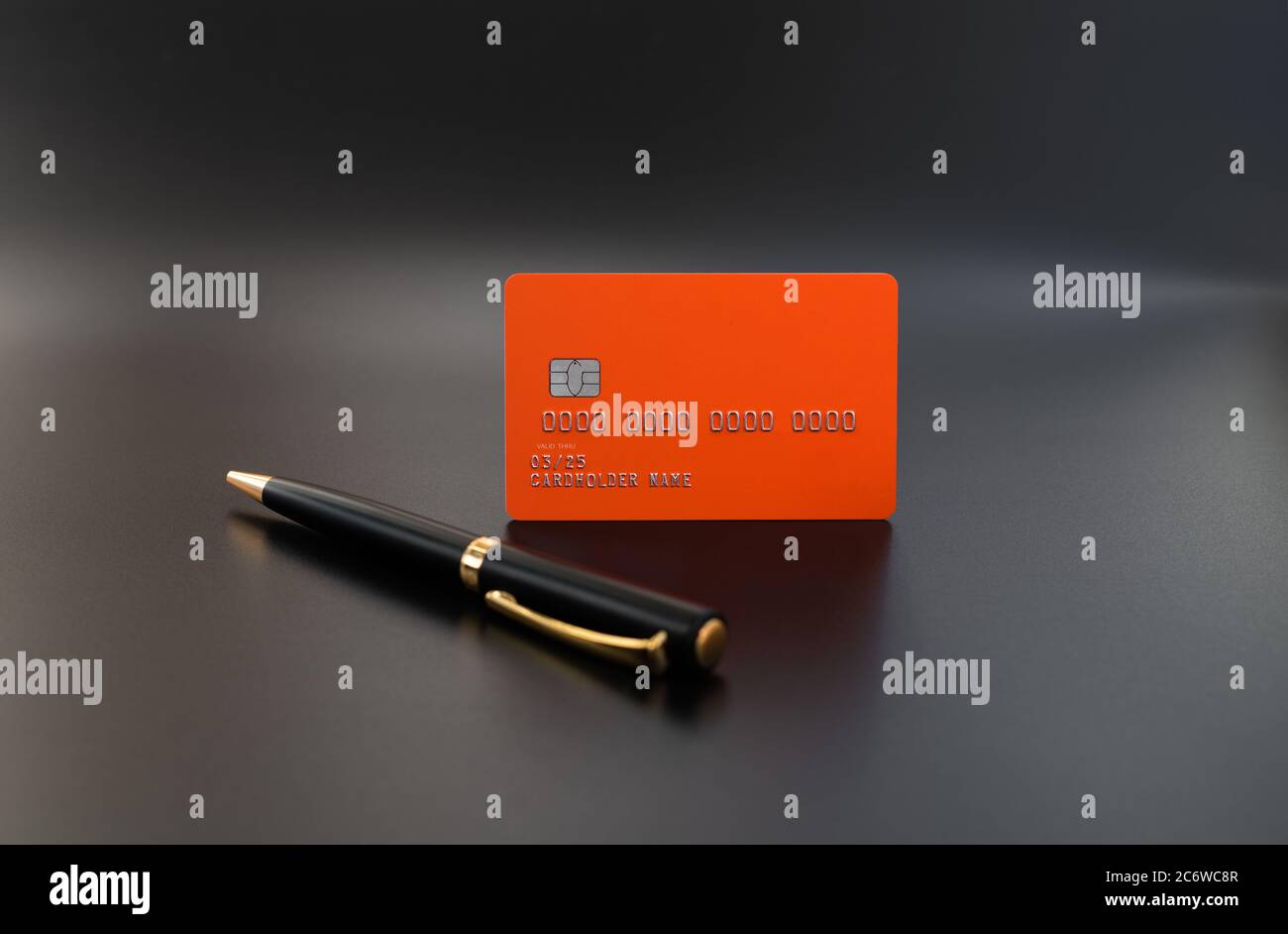 Premium orange credit card with pen on dark background Stock Photo - Alamy