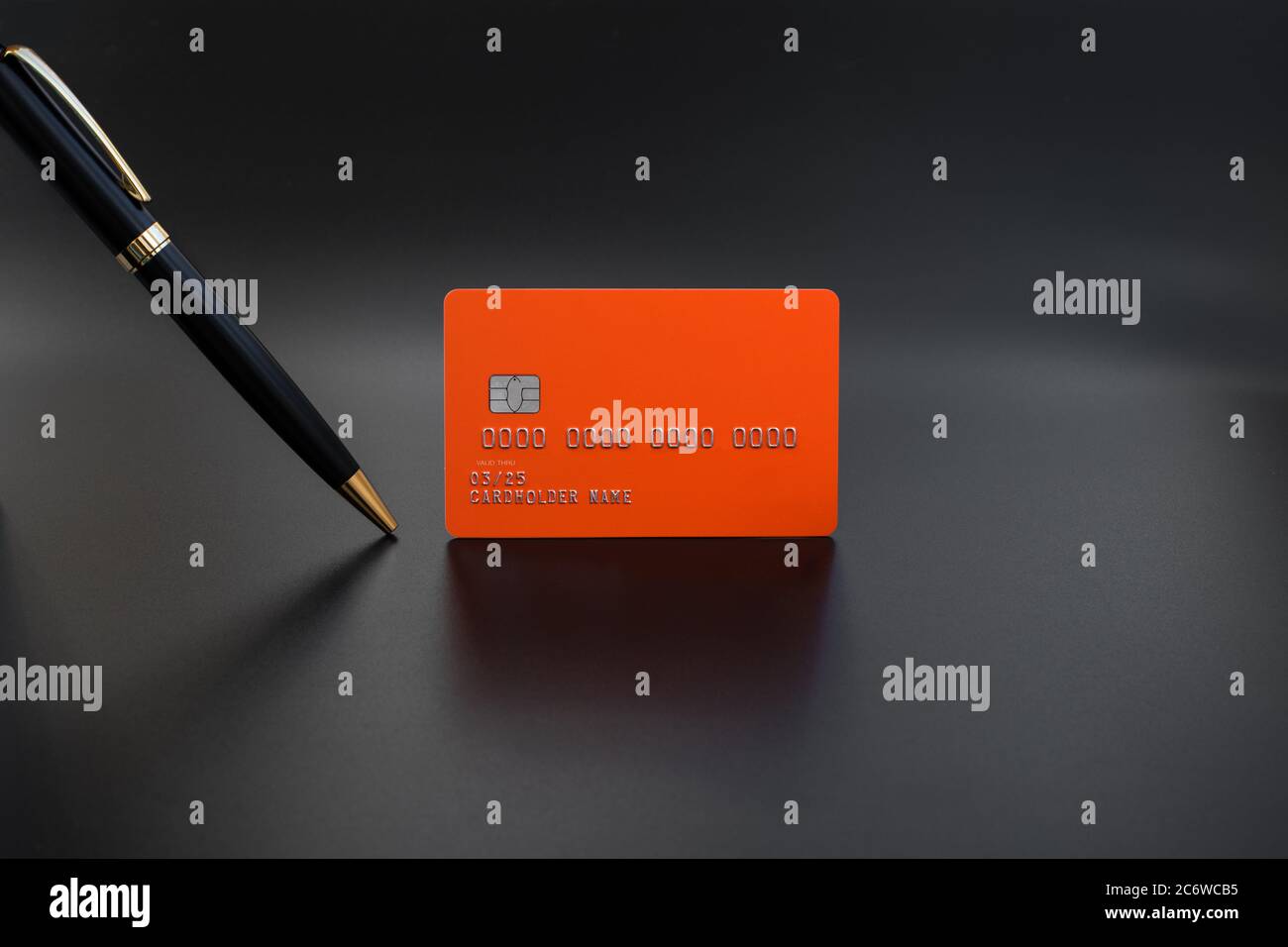 Orange credit card with luxury pen on dark background Stock Photo - Alamy