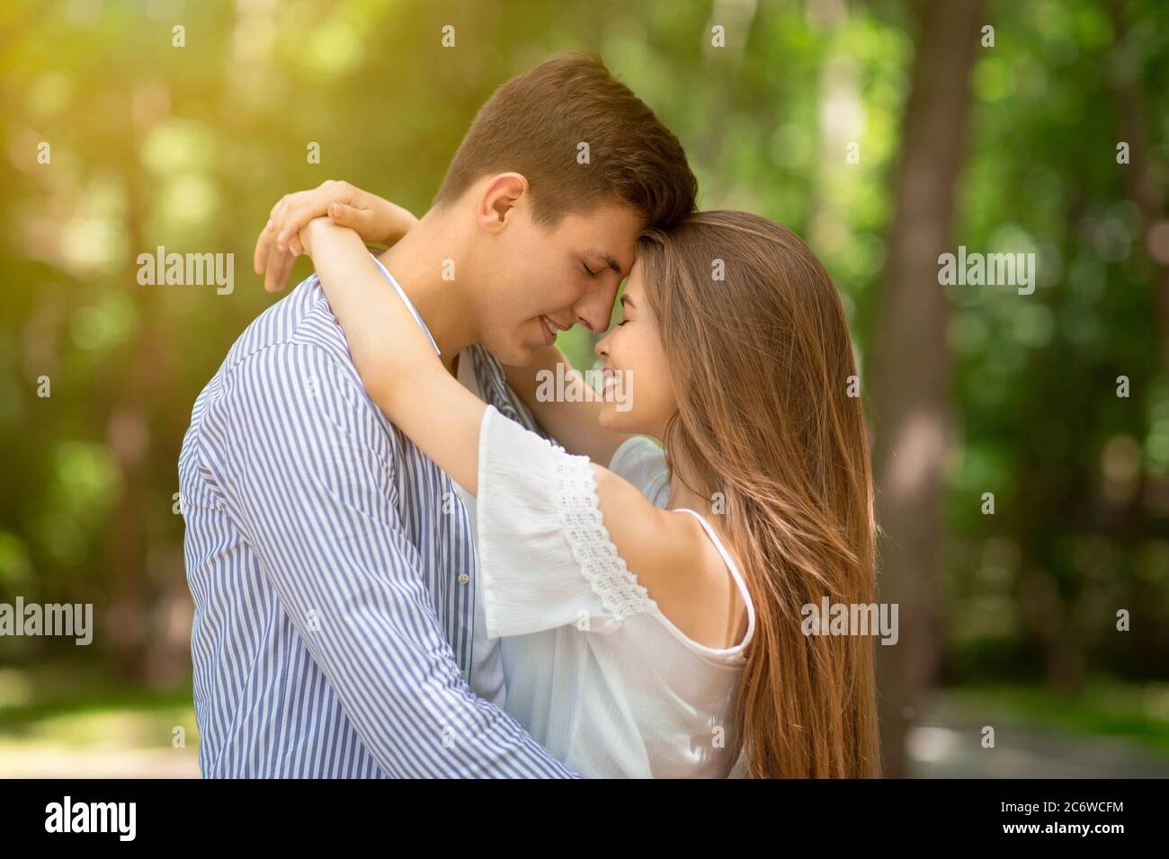 Young couple hugging and touching their foreheads on romantic date at ...