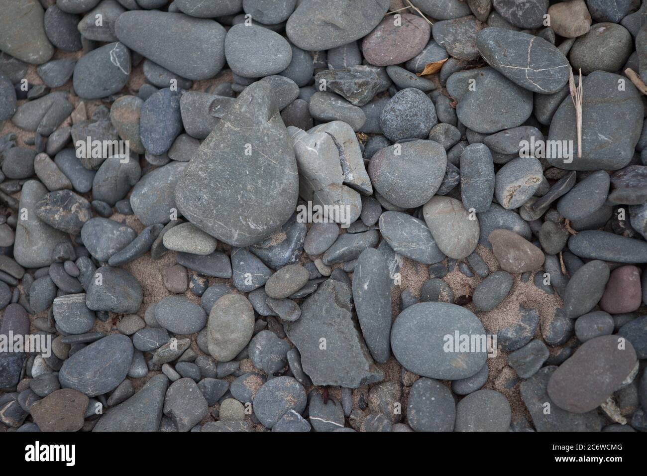 A shattered stone amongst a pile of stones on beach Stock Photo - Alamy