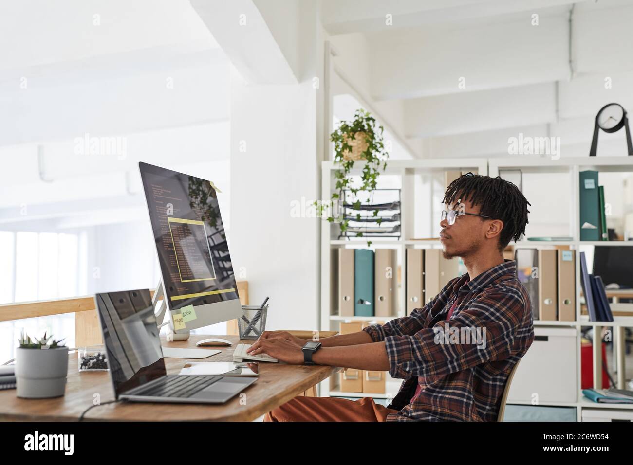 Side View Portrait Of African American It Developer Typing On Keyboard With Black And Orange