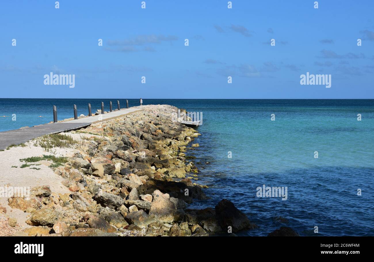 Rock jetty extending into blue tropical waters in Aruba Stock Photo - Alamy