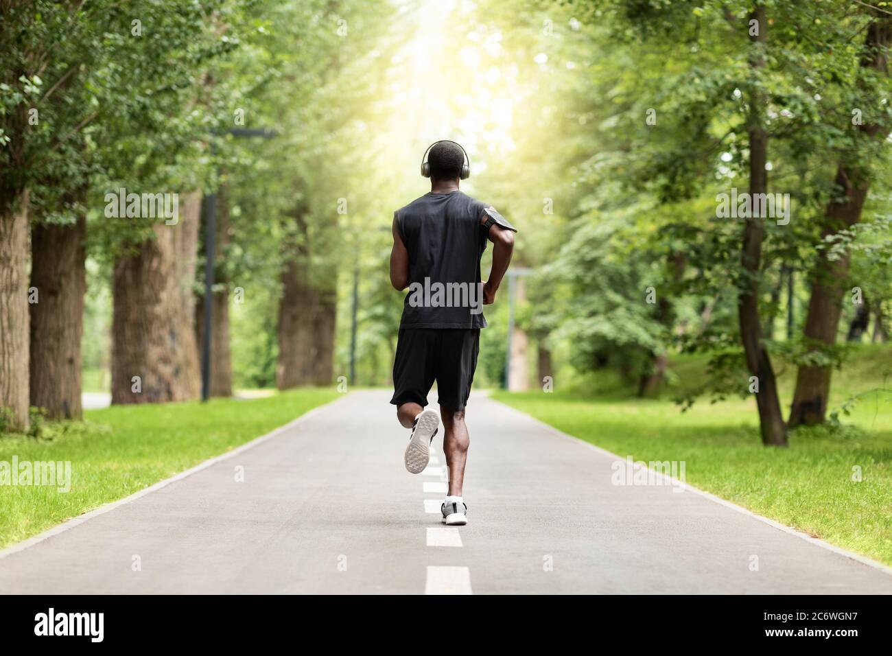 Back view of black guy jogging by park path Stock Photo - Alamy