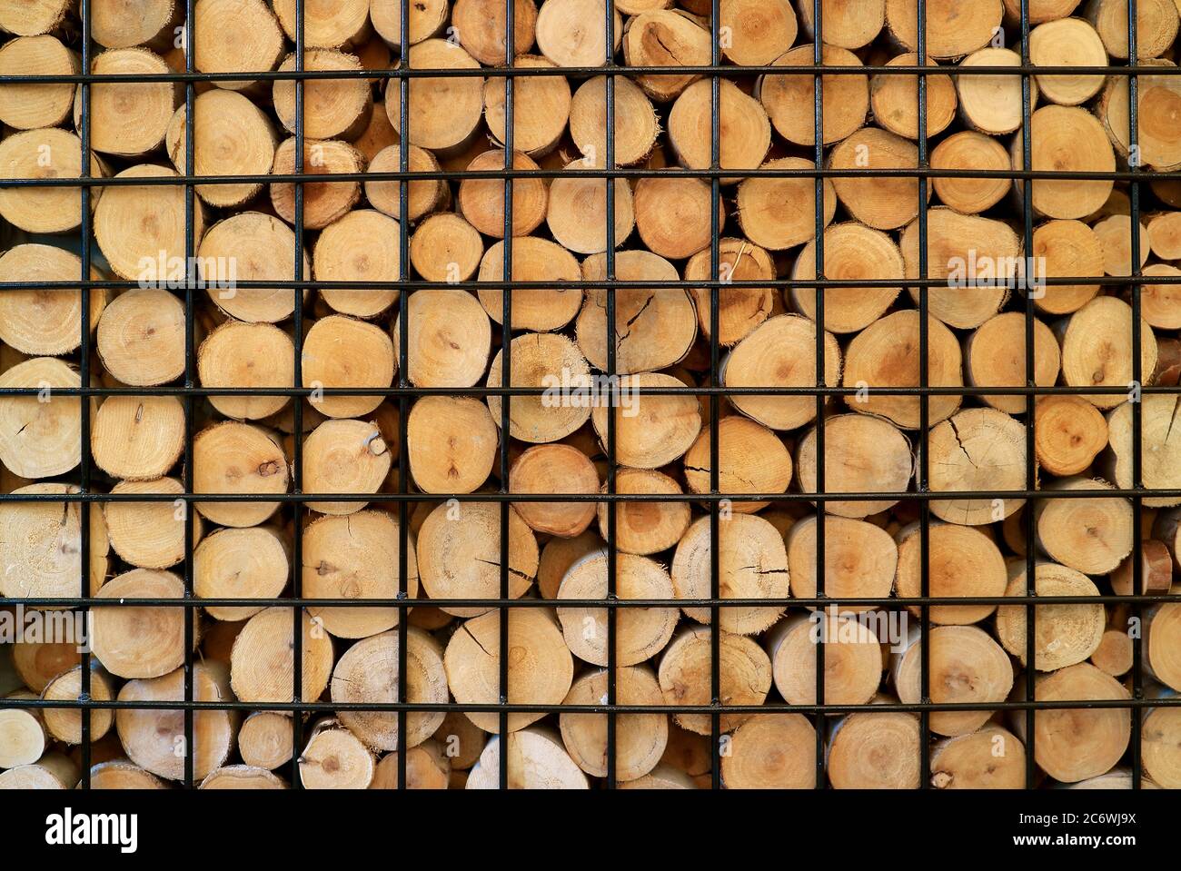 Stack of cut log woods in a metal cage for background or banner Stock ...