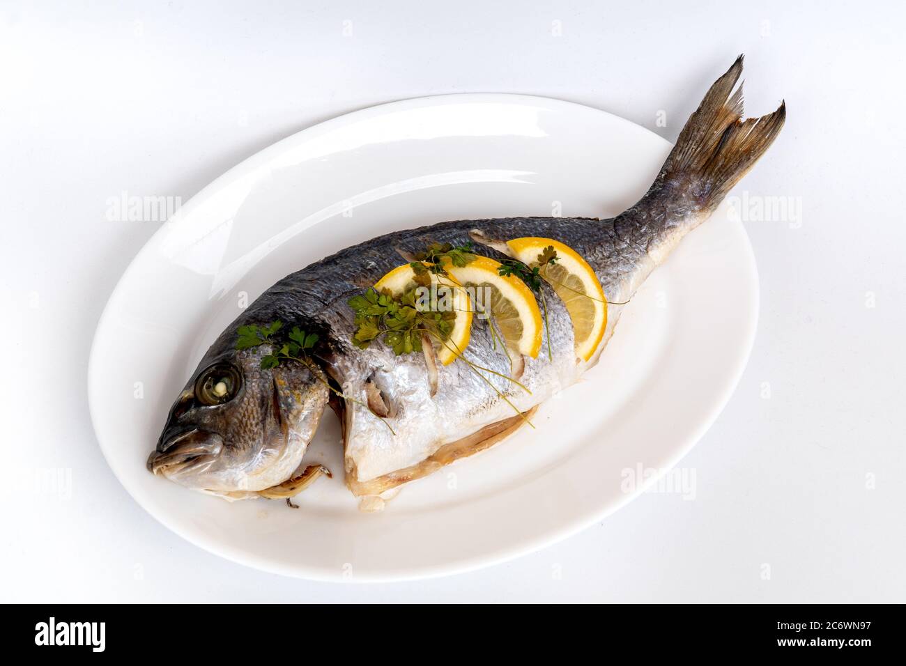 Dorada fish fried with lemon and parsley on a white plate and white ...