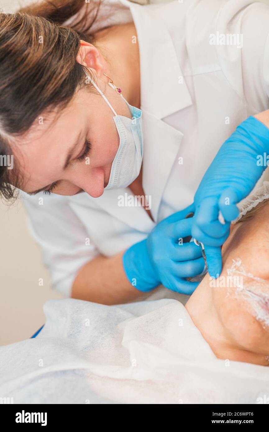 Female doctor makes an injection into the facial muscles for tightening ...