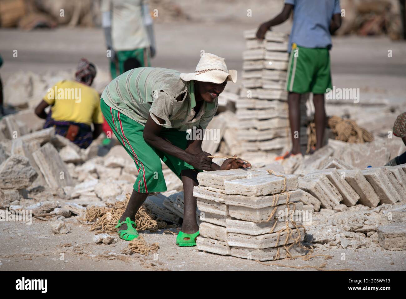 An Afar salt miner ties salt blocks to be taken by camel caravan to be ...