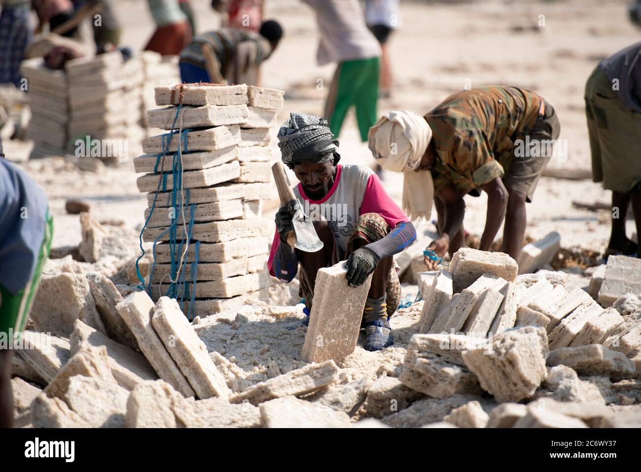 An Afar salt miner chops a block of salt before it is taken to be sold ...