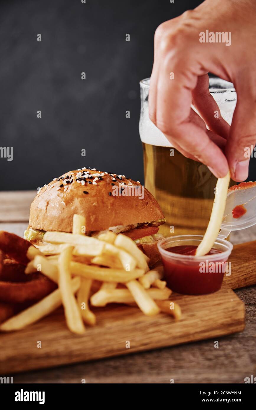 Different types of fastfood and snacks and glass of beer on table ...