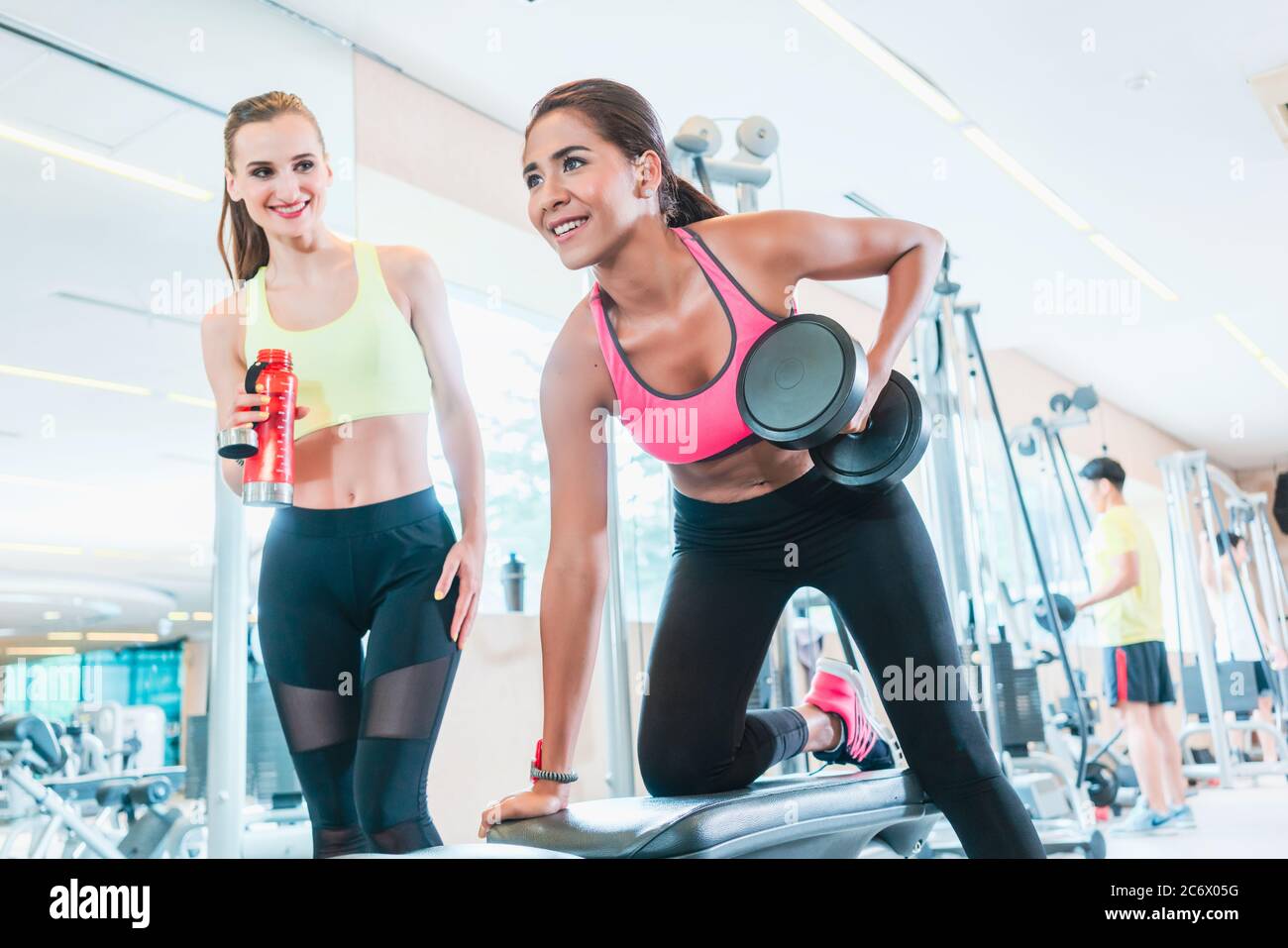 Powerful young woman smiling while rowing with one arm in a trendy ...