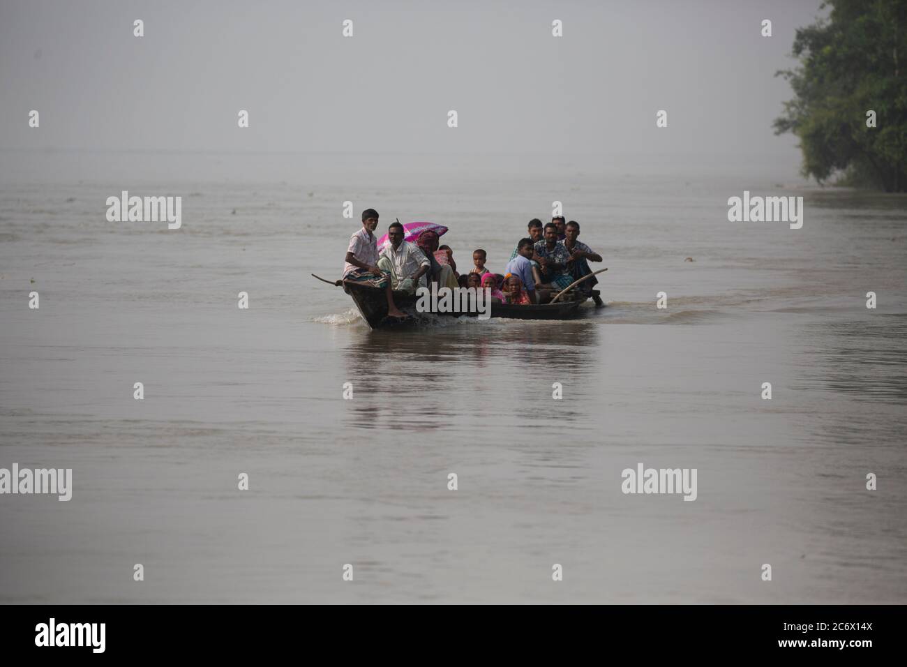 Flood affected people ride on a boat as they crossing the Brahmaputra ...