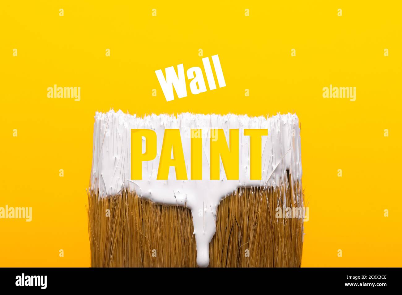 Paintbrush with white paint and inscription wall paint, over yellow ...