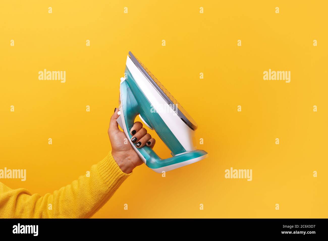 new modern iron in hand over yellow background Stock Photo - Alamy
