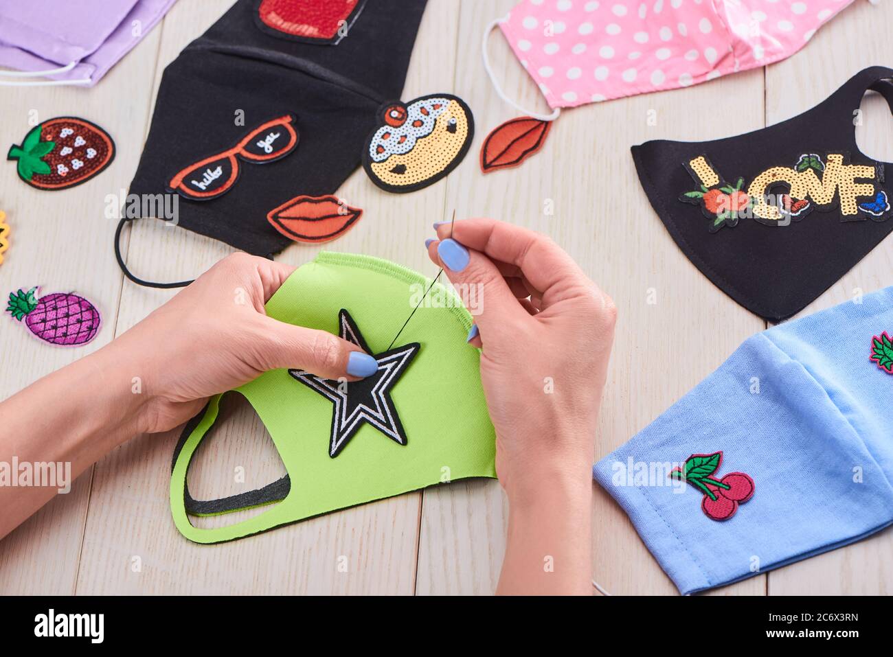 Woman sewing embroidered patches to face masks Stock Photo - Alamy
