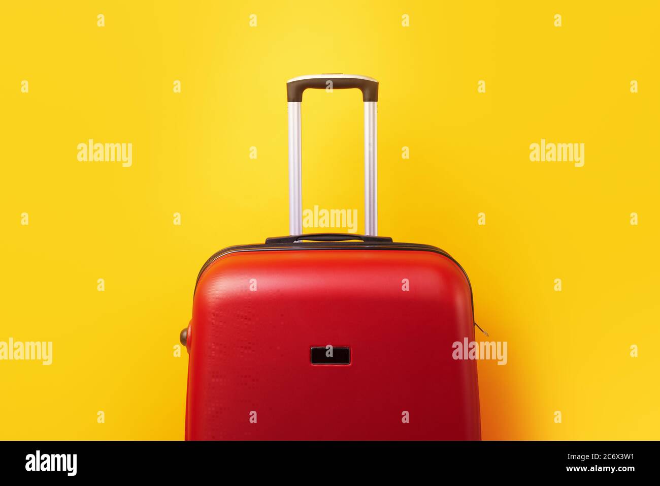 red travel suitcase close up over yellow background Stock Photo - Alamy