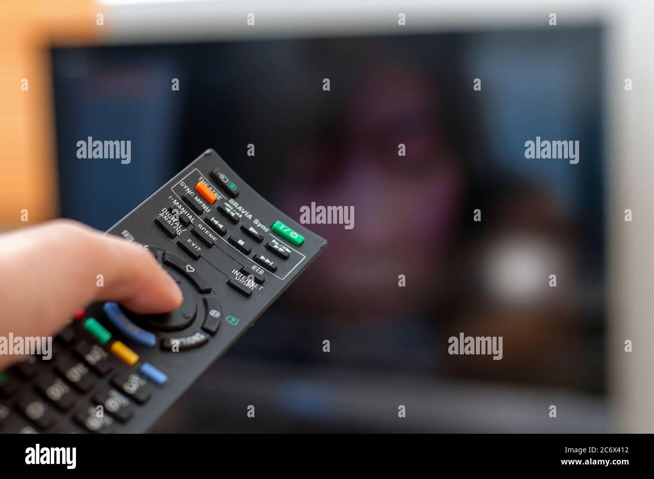 Remote control pointing towards the TV showing a woman just barely ...