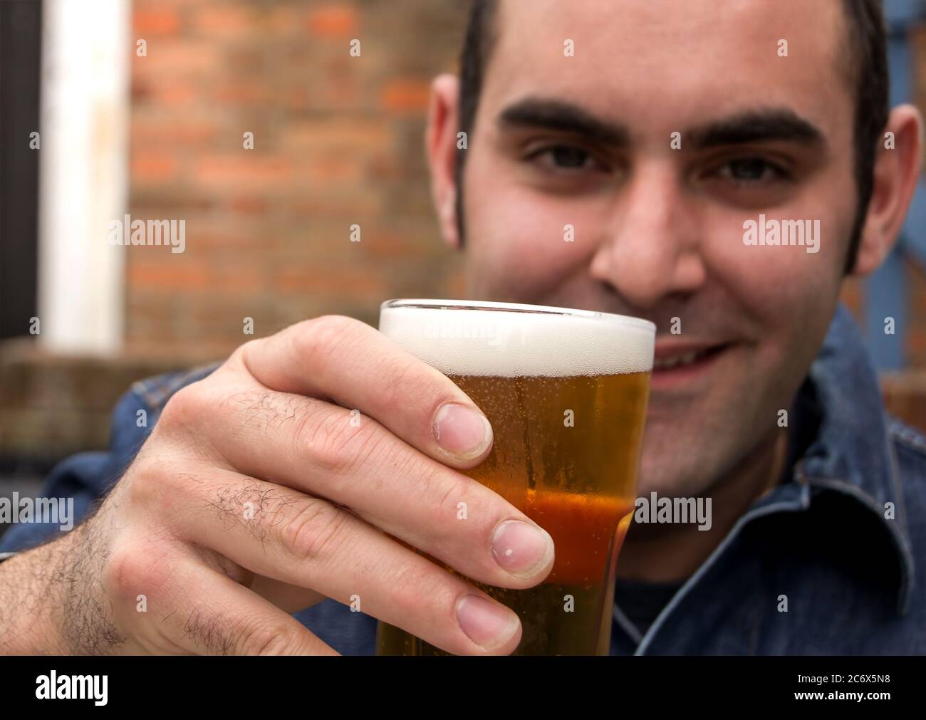 Man raising a glass of beer in a pub Stock Photo - Alamy
