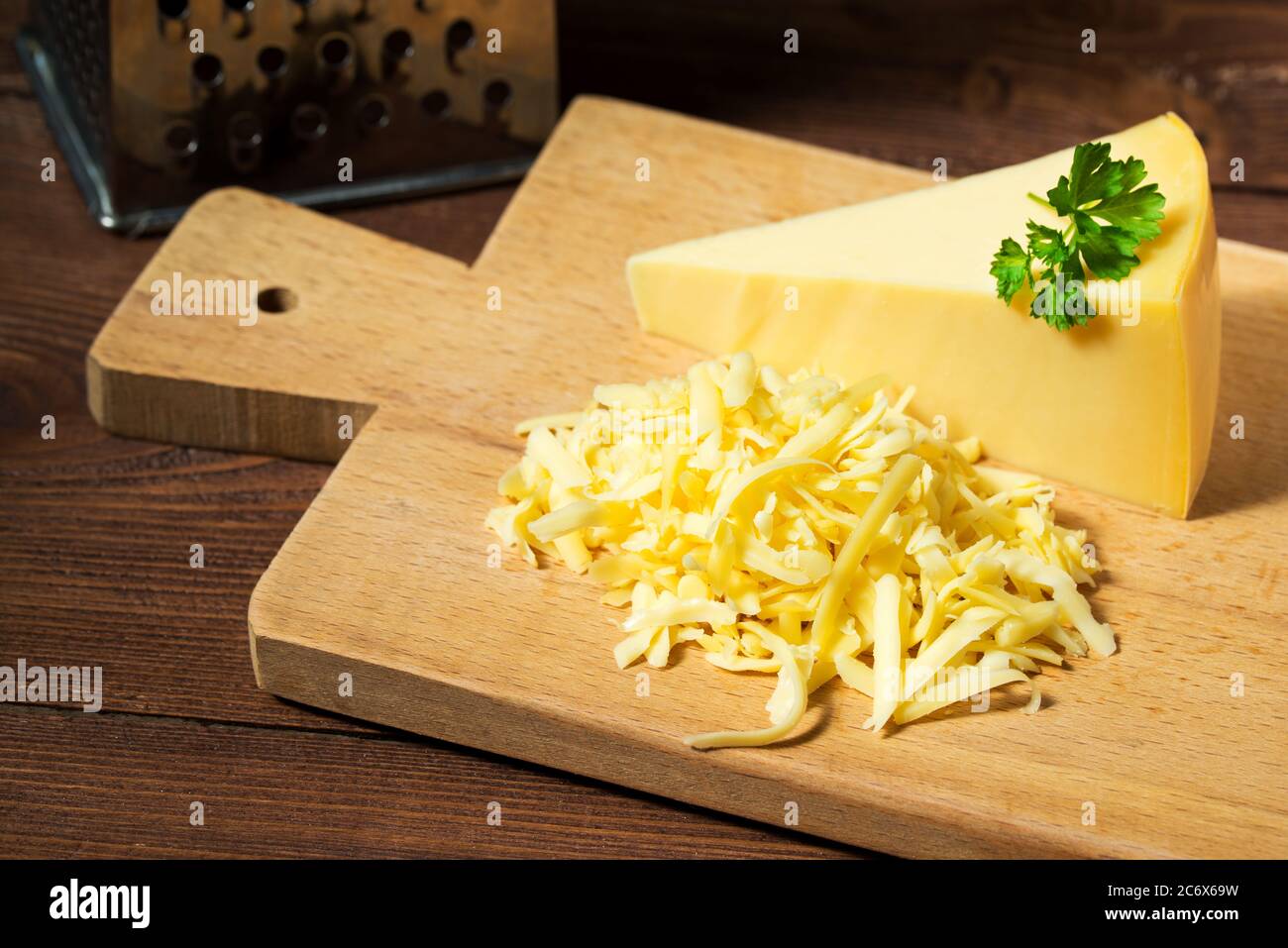 Grated cheese and cheese triangle on wooden cutting board Stock Photo ...