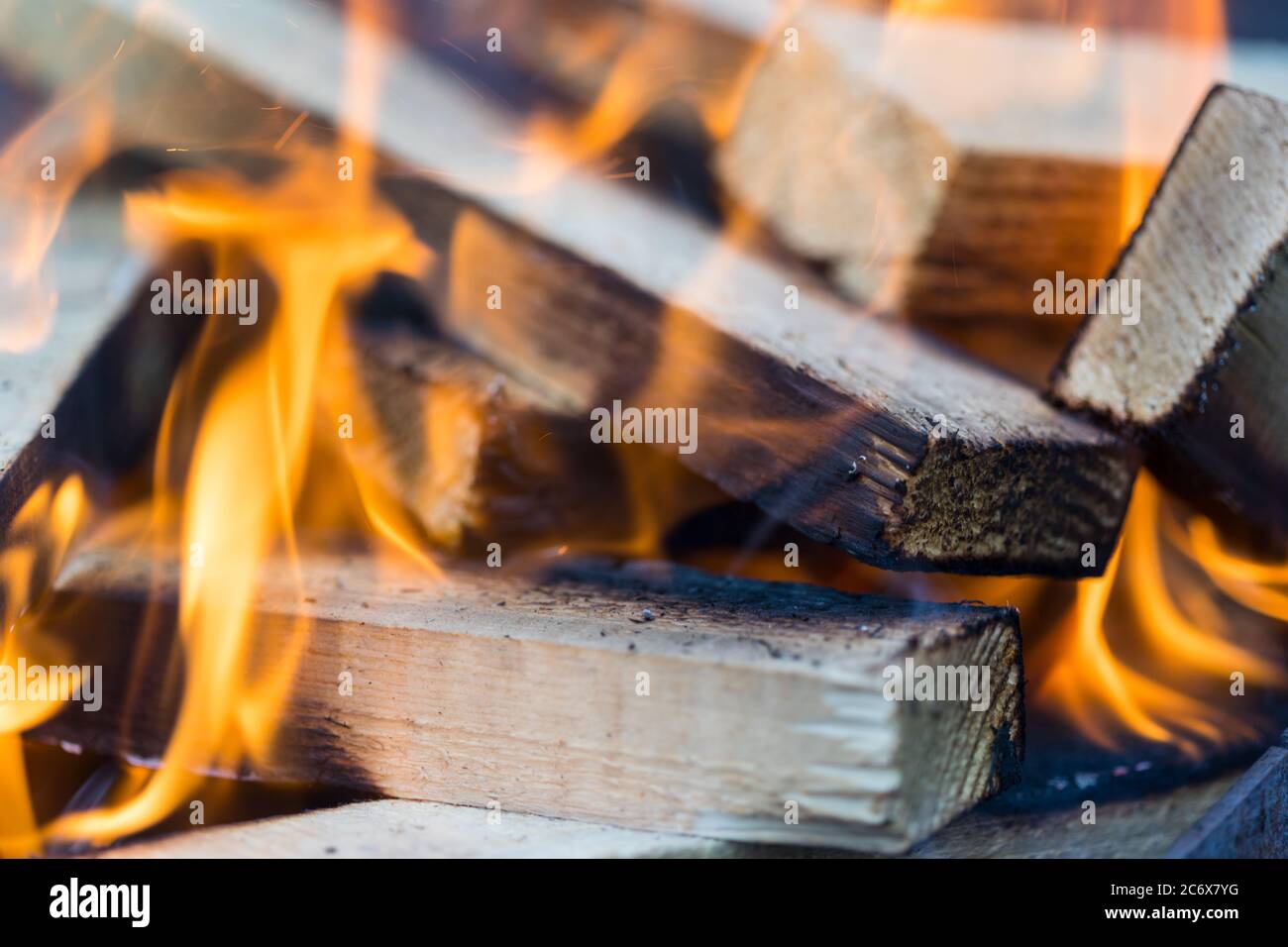 Flame incinerates firewood and transforms it ashes, close up, shallow ...