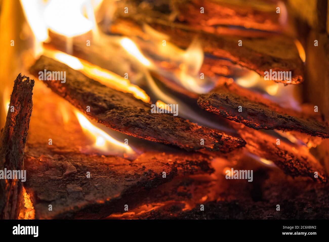 Flame incinerates firewood and transforms it ashes, close up, shallow ...