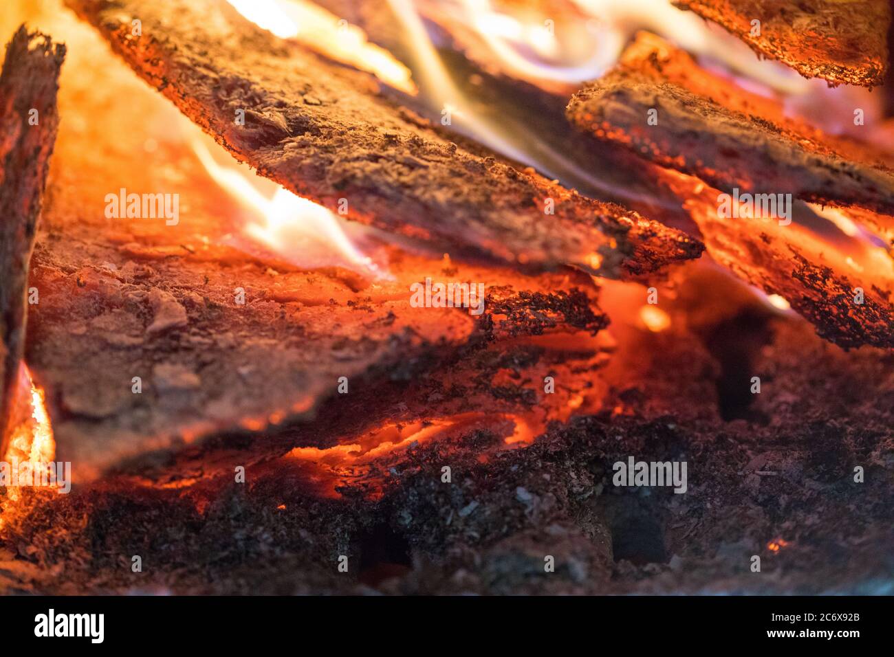 Flame incinerates firewood and transforms it ashes, close up, shallow ...