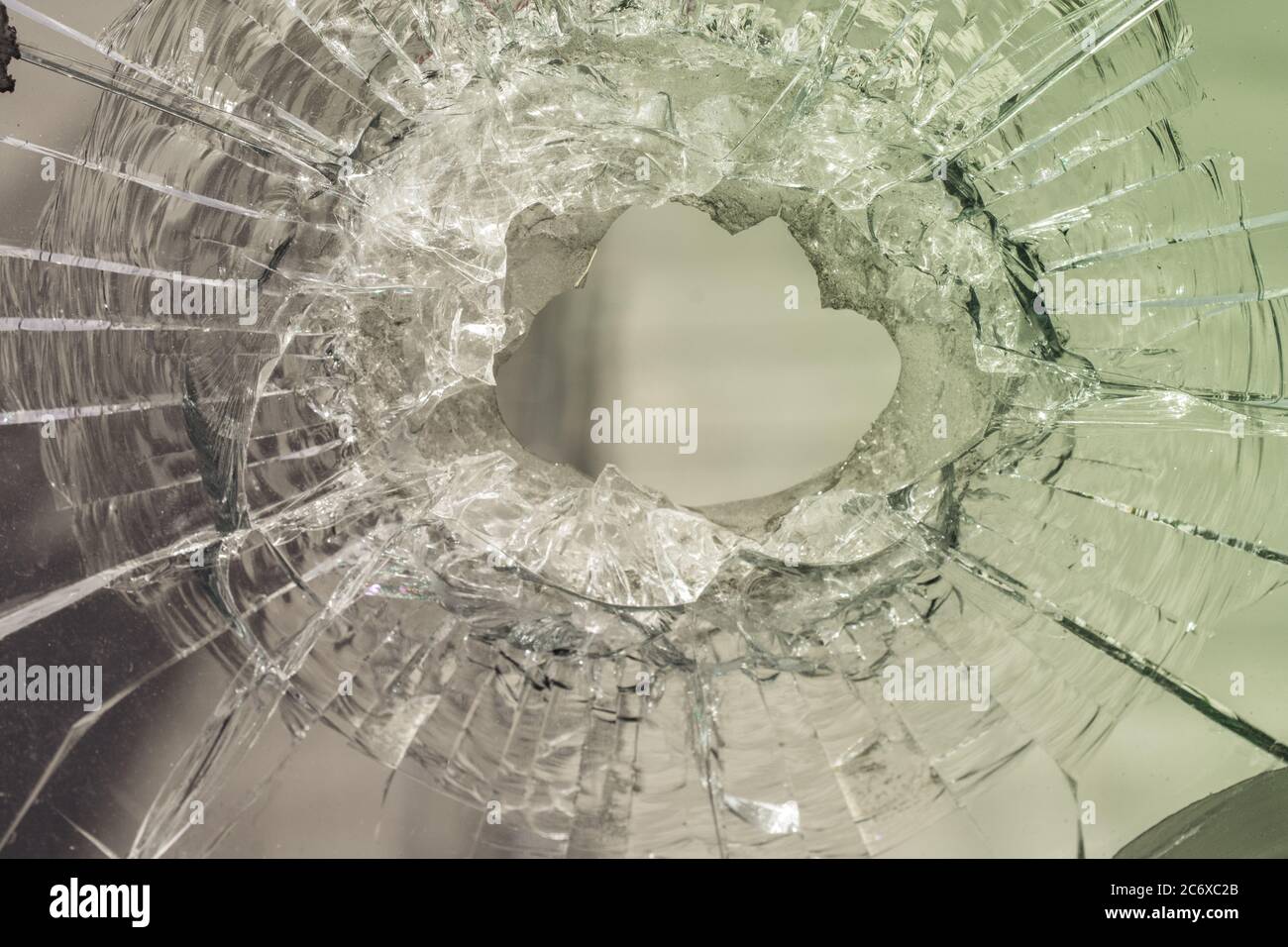 Damaged glass with a hole in shatters into small pieces Stock Photo - Alamy