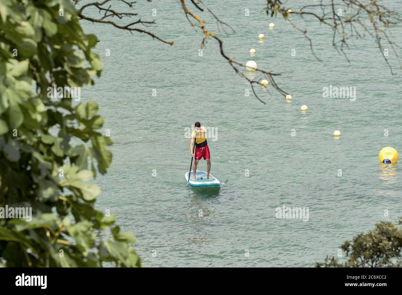 man in paddle surf enjoys calm seas on the beach of Islares, Cantabria ...