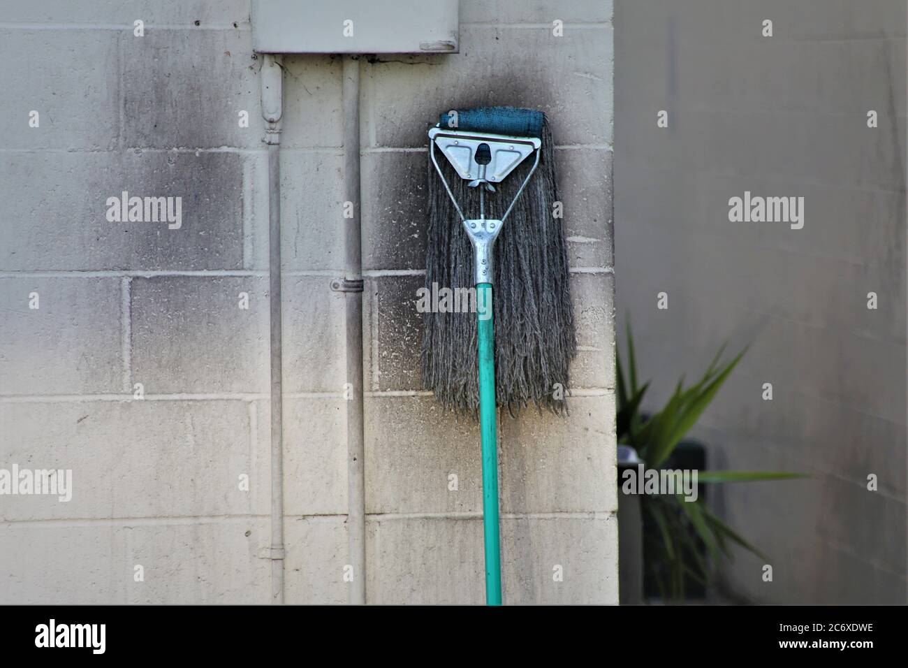 Old style mop leaning against the wall of house as if the woman doing ...