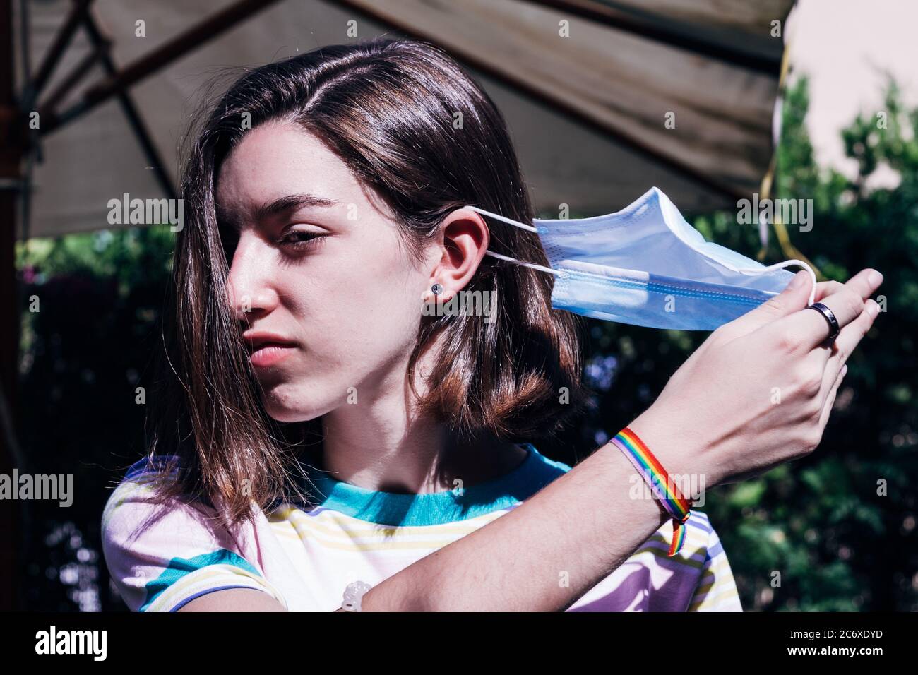 A Teenage girl holding her mask after taking it off, happy to be able ...