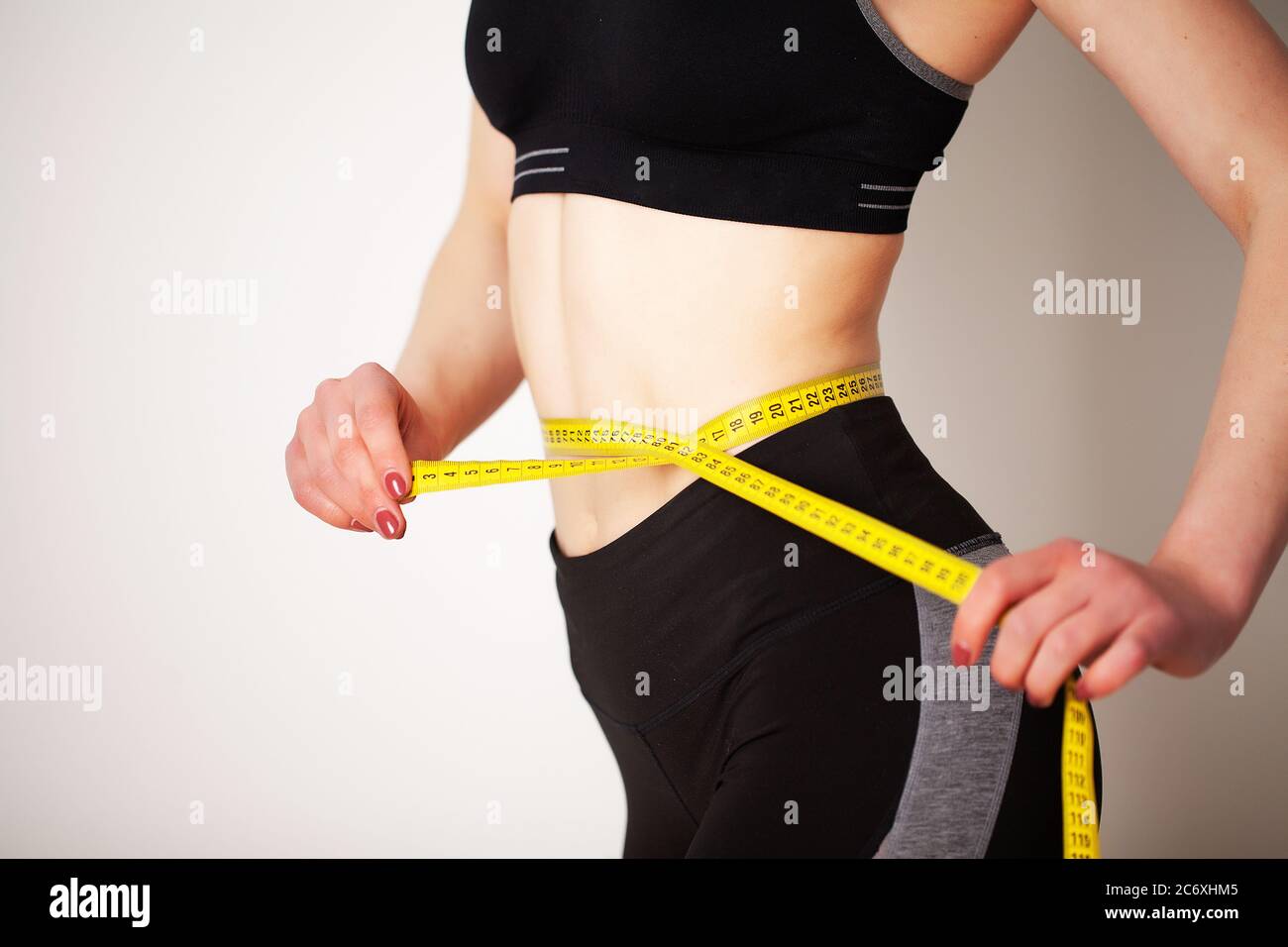 Woman with a sporty figure measures the size of her waist Stock Photo ...