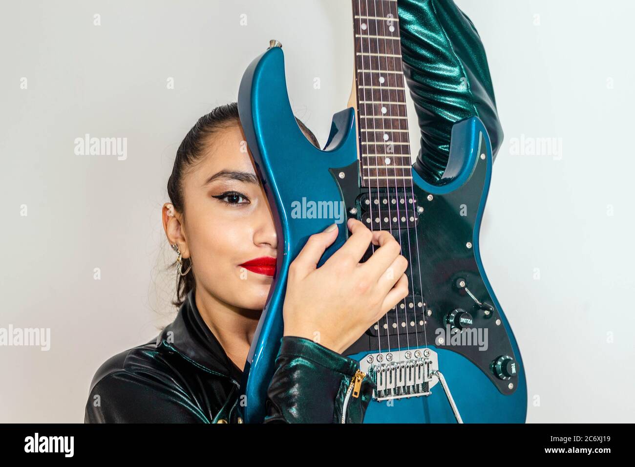 Teen girl with a guitar in front of her face and showing only half of ...