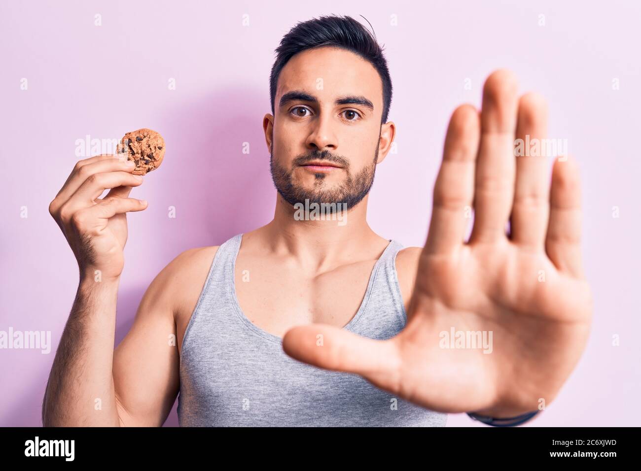 Young handsome man with beard wearing sleeveless t-shirt eating ...