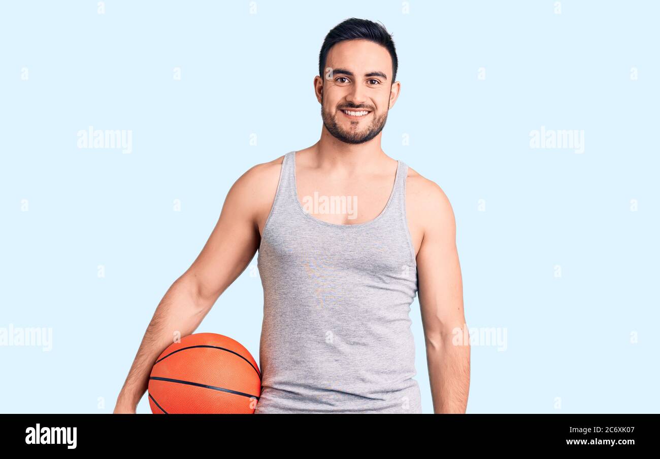 Young handsome man holding basketball ball looking positive and happy ...