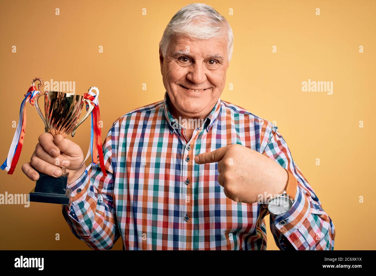 Senior handsome hoary champion man holding trophy award for victory ...