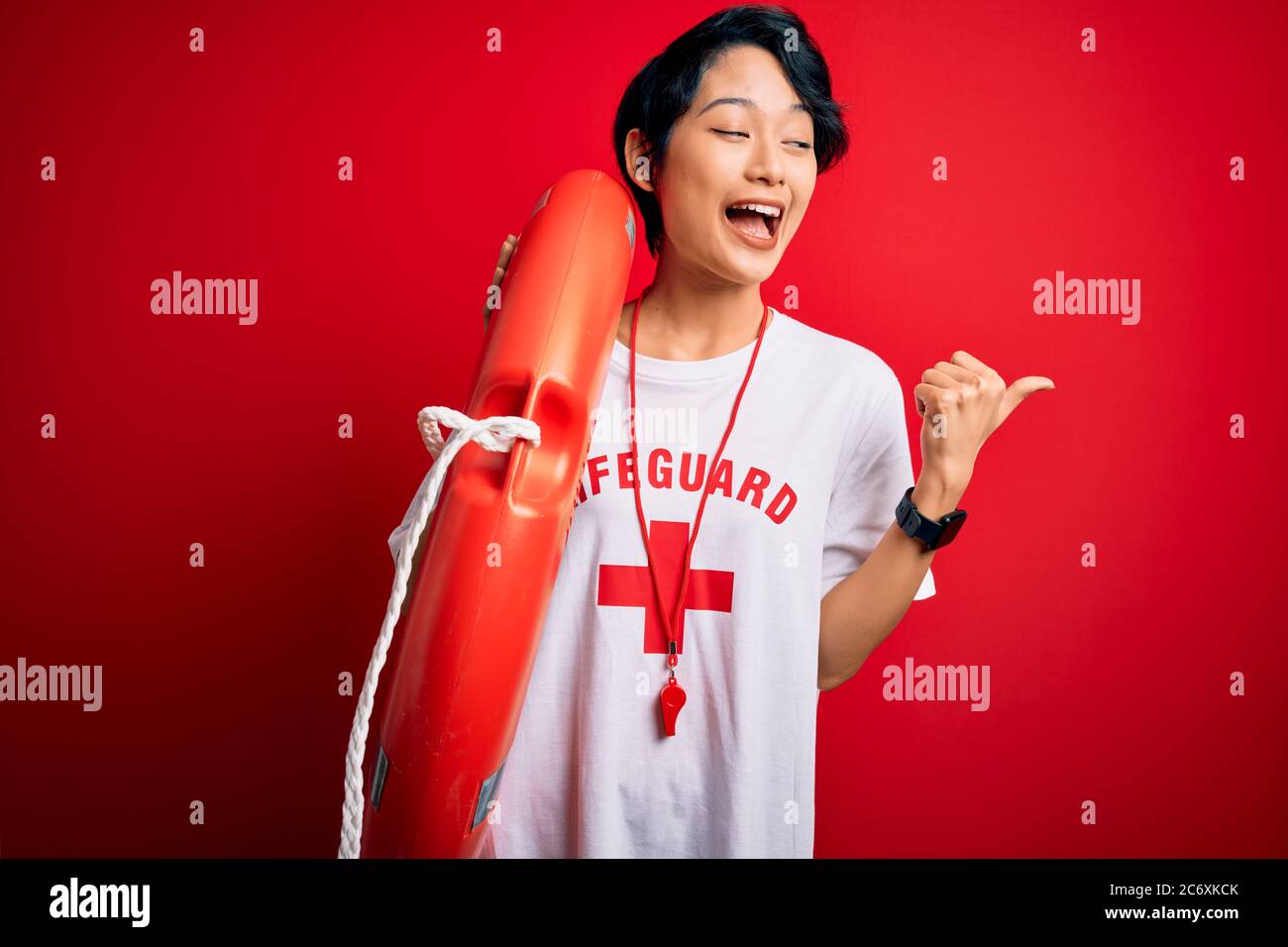 Young beautiful asian lifeguard girl using whistle holding orange float ...