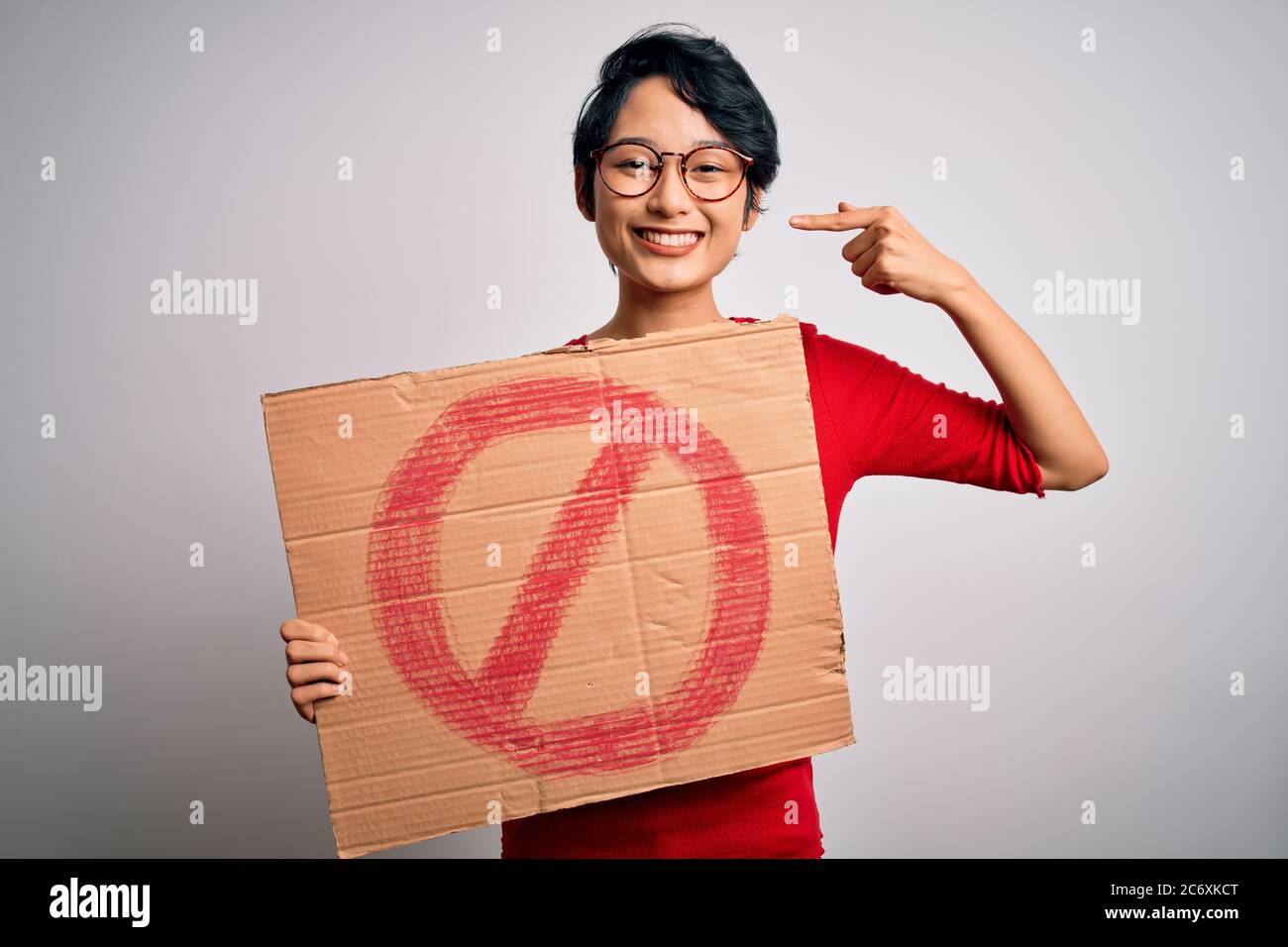 Young beautiful asian girl holding banner with prohibited signal over ...