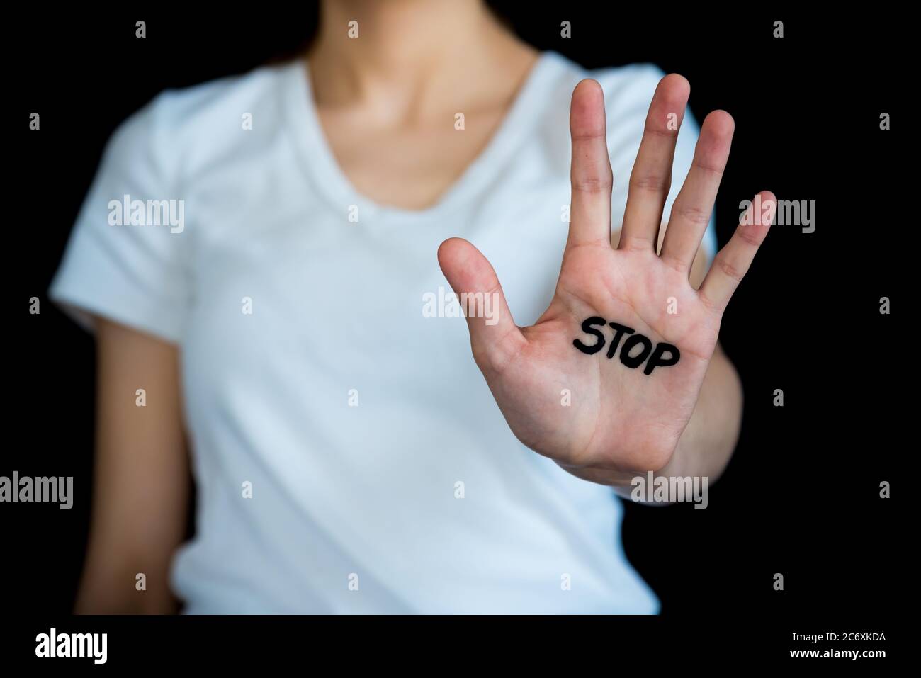 Woman holding out hand in stop gesture with word Stop written on open ...