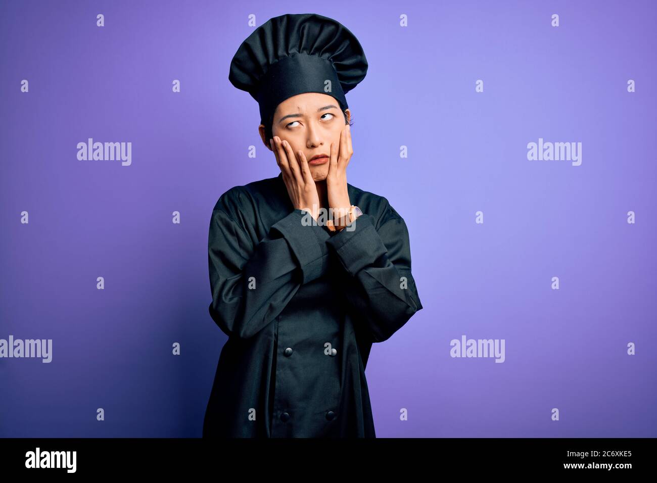 Young beautiful chinese chef woman wearing cooker uniform and hat over ...