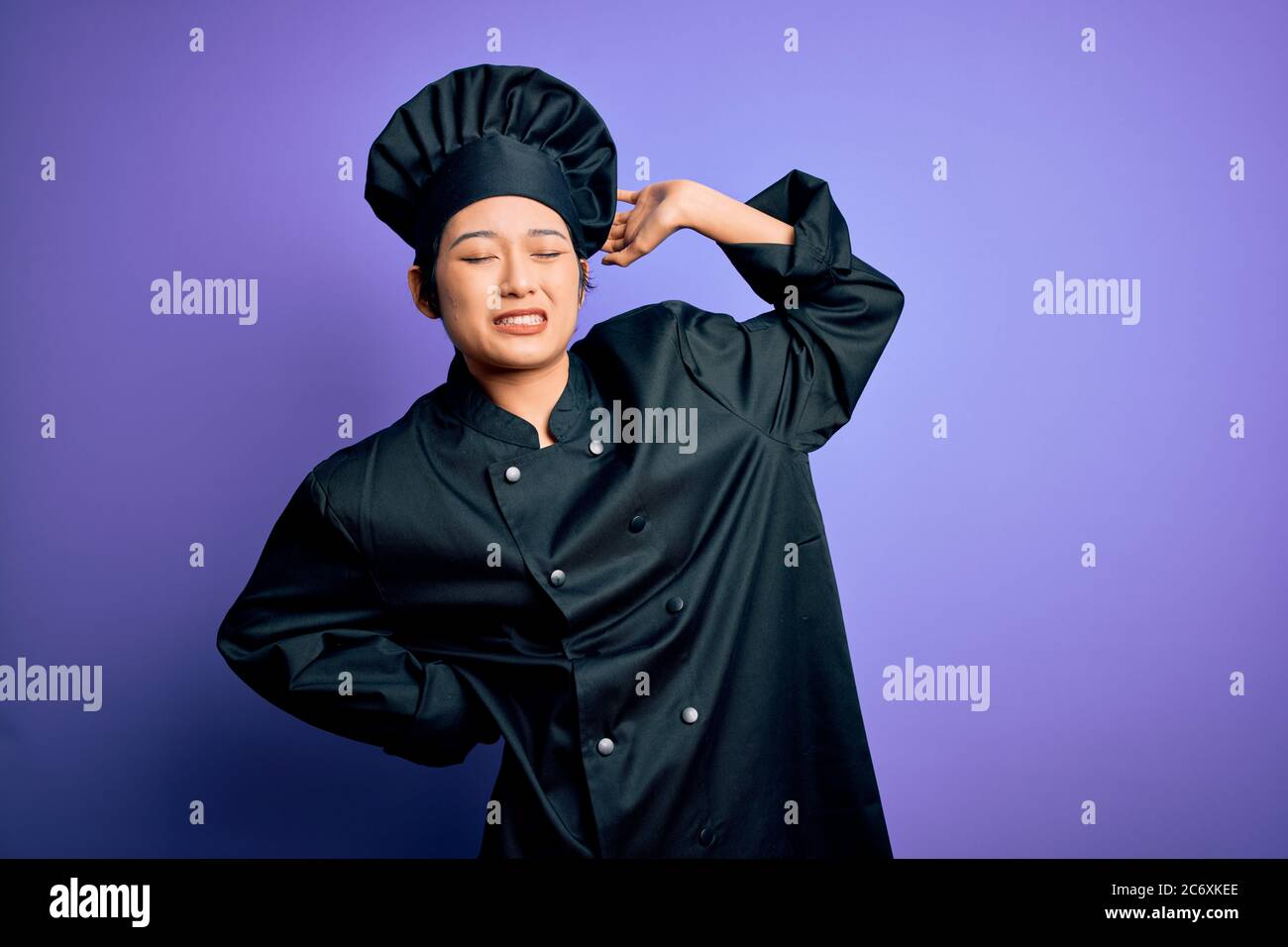 Young beautiful chinese chef woman wearing cooker uniform and hat over ...