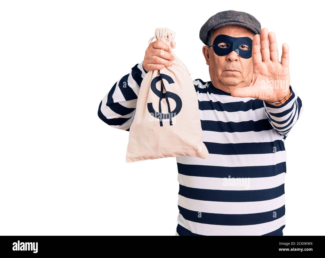 Senior handsome man wearing burglar mask holding money bag with open ...