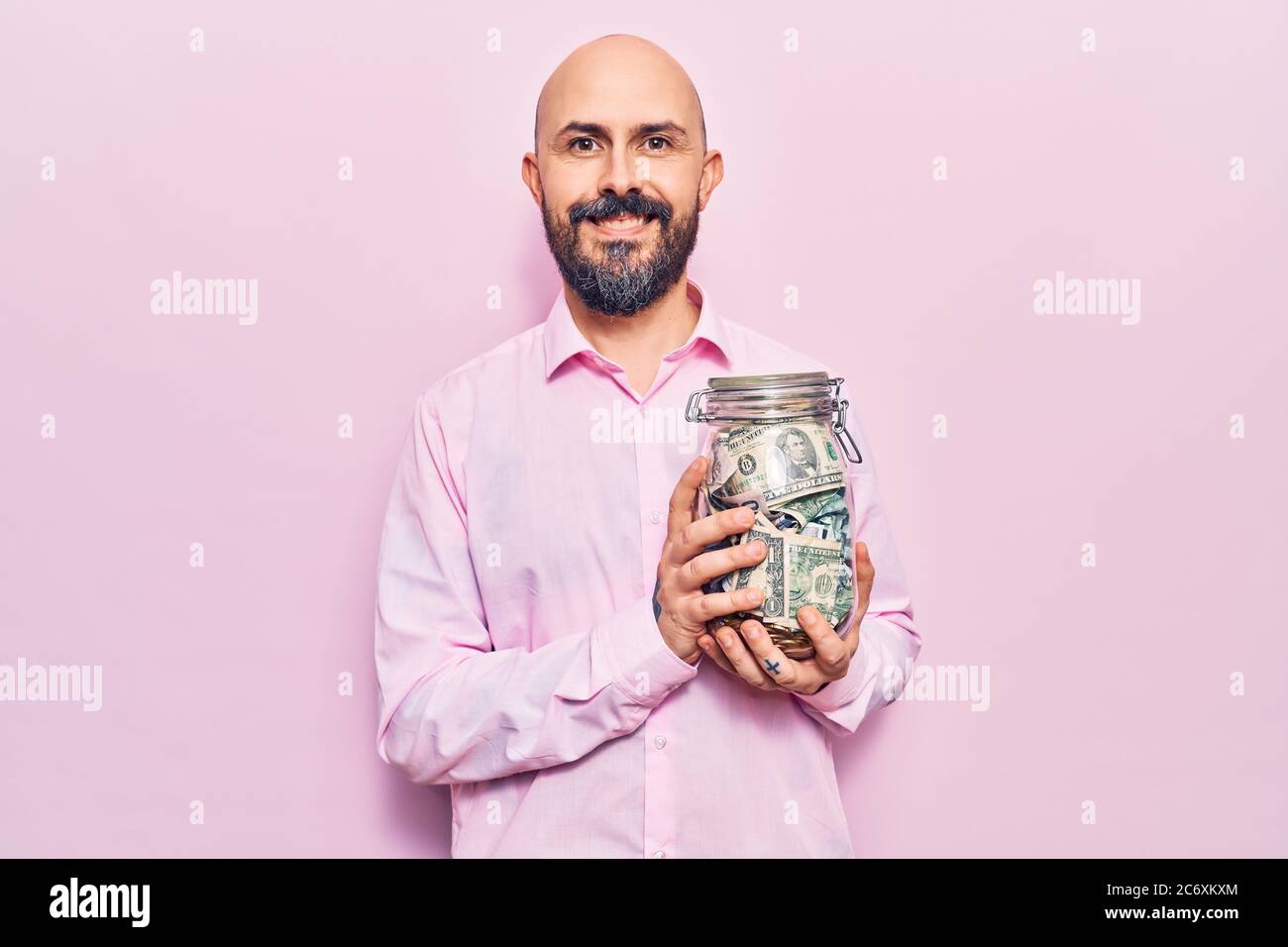 Young handsome man holding jar with savings looking positive and happy ...