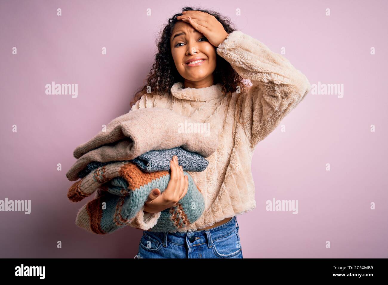 Beautiful shopkeeper woman with curly hair holding stack of clothes ...