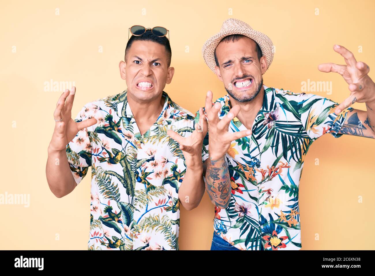 Young gay couple of two men wearing summer hat and hawaiian shirt ...