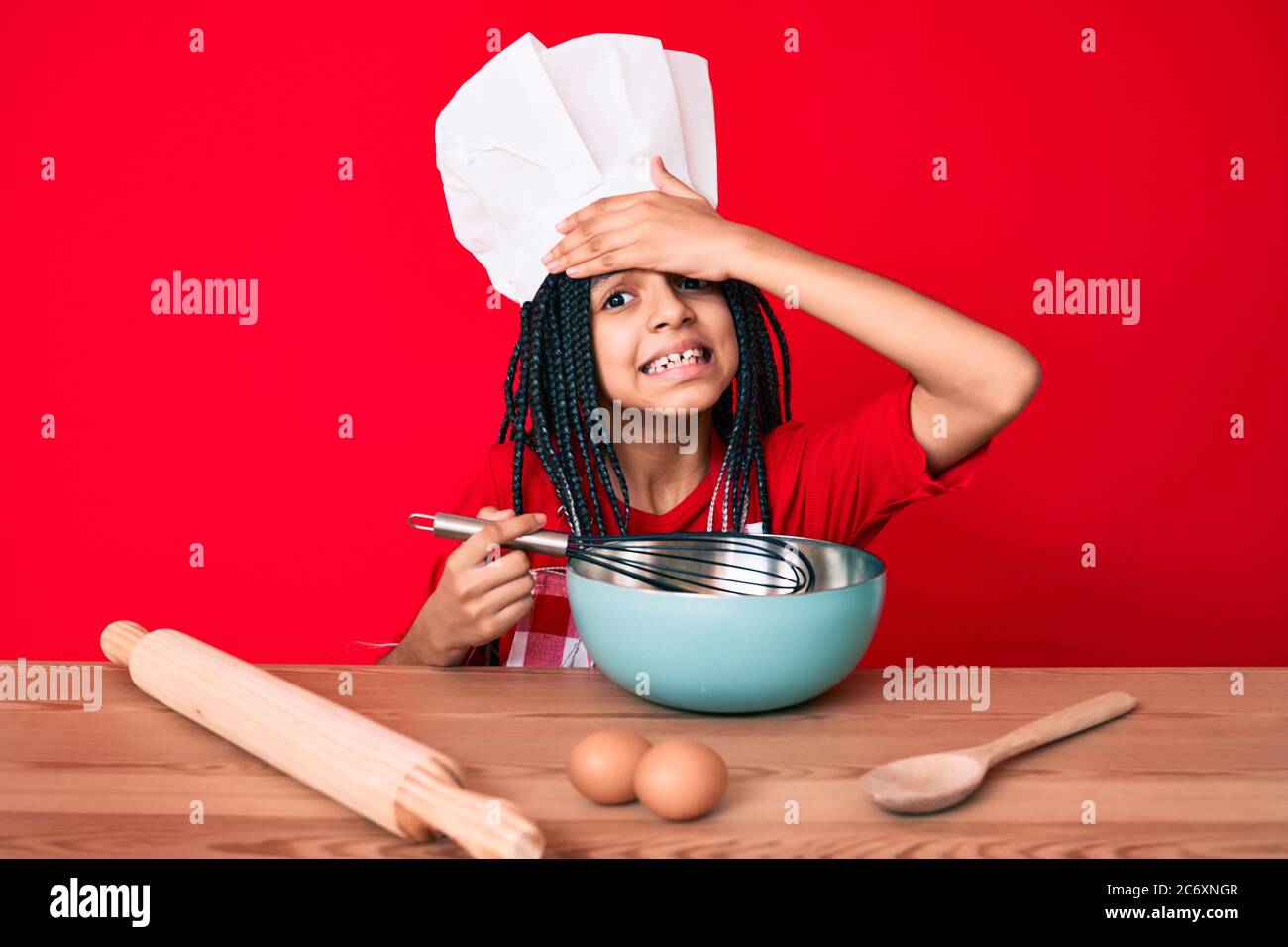Young african american girl child with braids cooking using baker whisk ...