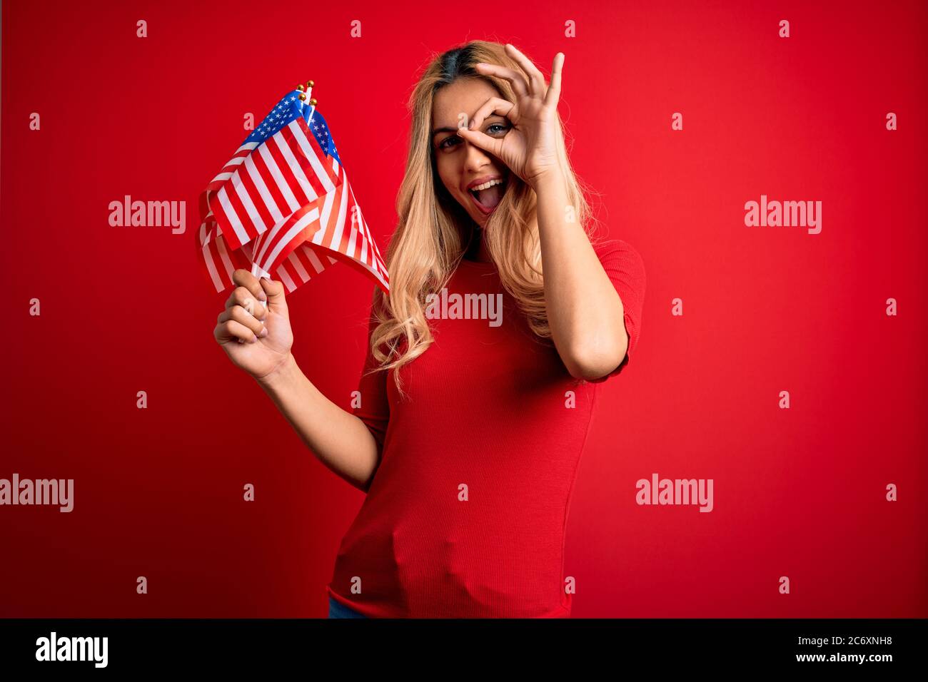 Beautiful blonde patriotic woman holding united states flags ...
