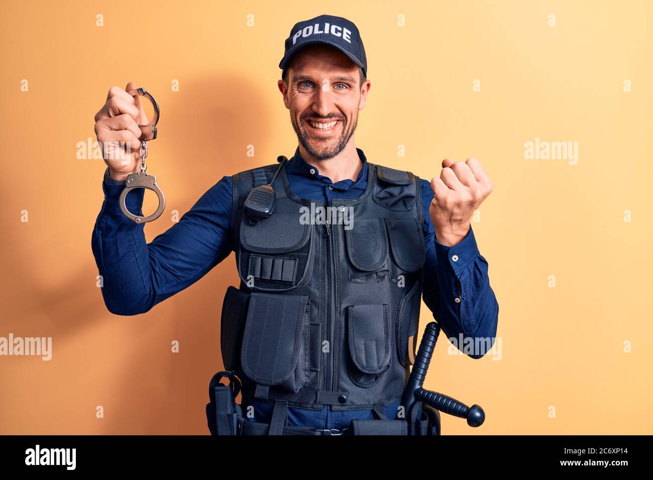 Handsome policeman wearing uniform and bulletprof holding handcuffs ...