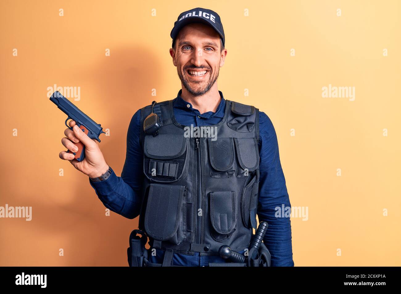 Handsome policeman wearing uniform and bulletprof holding gun over ...