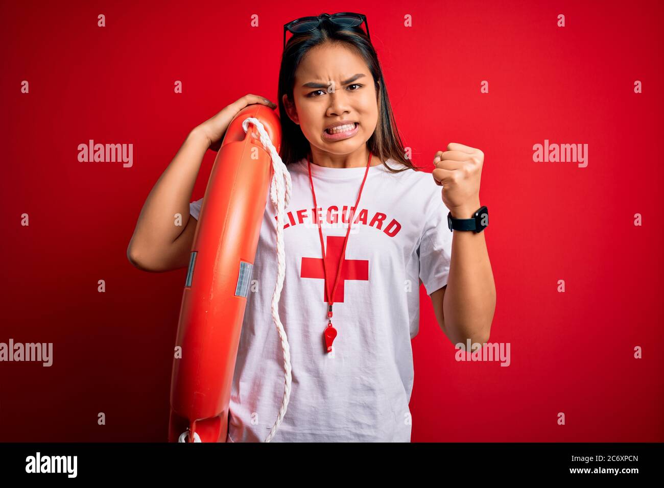 Young asian lifeguard girl wearing t-shirt with red cross using whistle ...